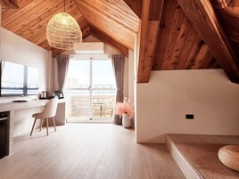 Quarto moderno no estilo loft, com teto inclinado, uma janela grande, escrivaninha com cadeira e uma cama.