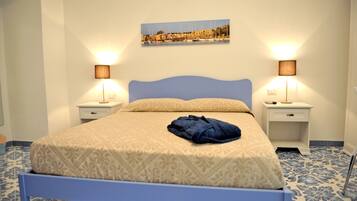 Quarto com uma cama, duas mesas de cabeceira, um criado-mudo, um quadro na parede e ladrilhos de chão estampados.