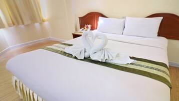 Quarto de hotel com uma cama bem arrumada, cabeceira de madeira e travesseiro branco.