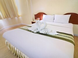 Quarto de hotel com uma cama bem arrumada, cabeceira de madeira e travesseiro branco.