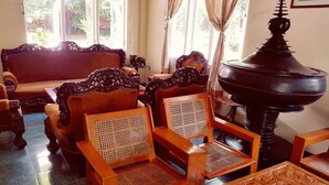 Quarto tradicional com mobiliário de madeira, incluindo um sofá e cadeiras, e um vaso decorativo grande.