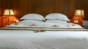 Uma cama bem arrumada com lençóis brancos, duas almofadas e flores decorativas.