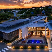 Um edifício moderno com piscina no terraço, painéis solares e vista para a paisagem circundante.