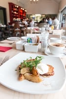 Uma mesa de jantar com um prato de comida, uma xícara de café e diversos acompanhamentos.
