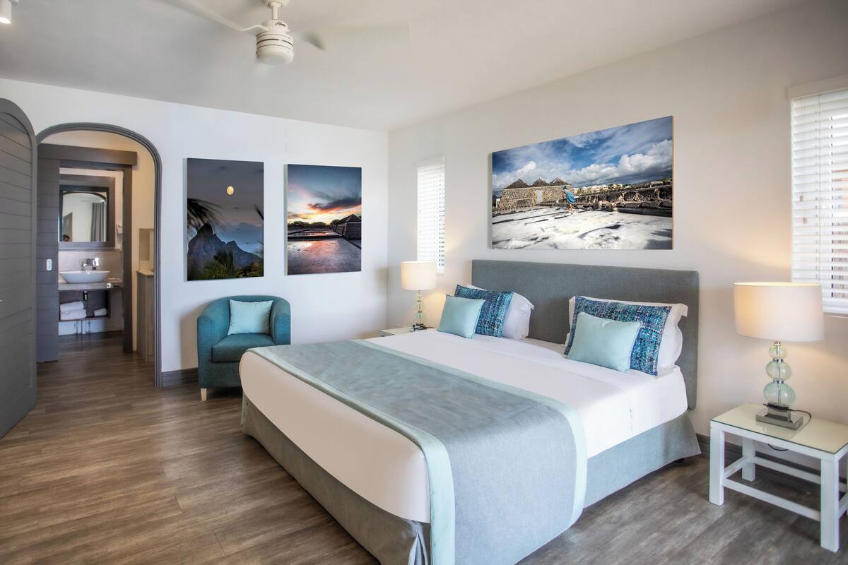 Quarto moderno com uma cama grande, uma cadeira e obras de arte nas paredes.