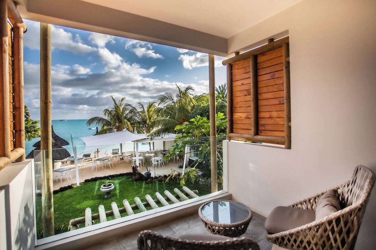 Varanda com vista para um jardim tropical e o oceano.