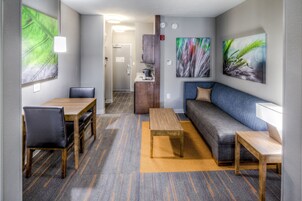 Quarto de hotel moderno com área de refeições, um sofá e uma pequena mesa.