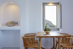 Uma área de jantar com mesa e cadeiras de madeira, decoração de peixe na parede, e janela com vista para o exterior.
