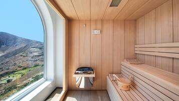 Uma sala de sauna com bancos de madeira, uma prateleira com aquecedor e uma janela com vista para uma paisagem montanhosa.
