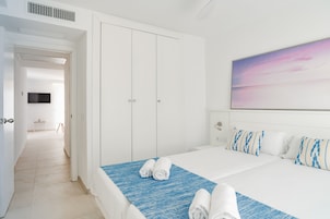 Quarto de hotel com cama, guarda-roupa amplo, televisão de tela plana e um quadro na parede.