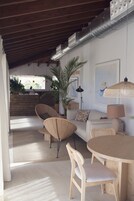 Um espaço aconchegante com móveis de vime, uma mesa de madeira redonda e um sofá com abajur.