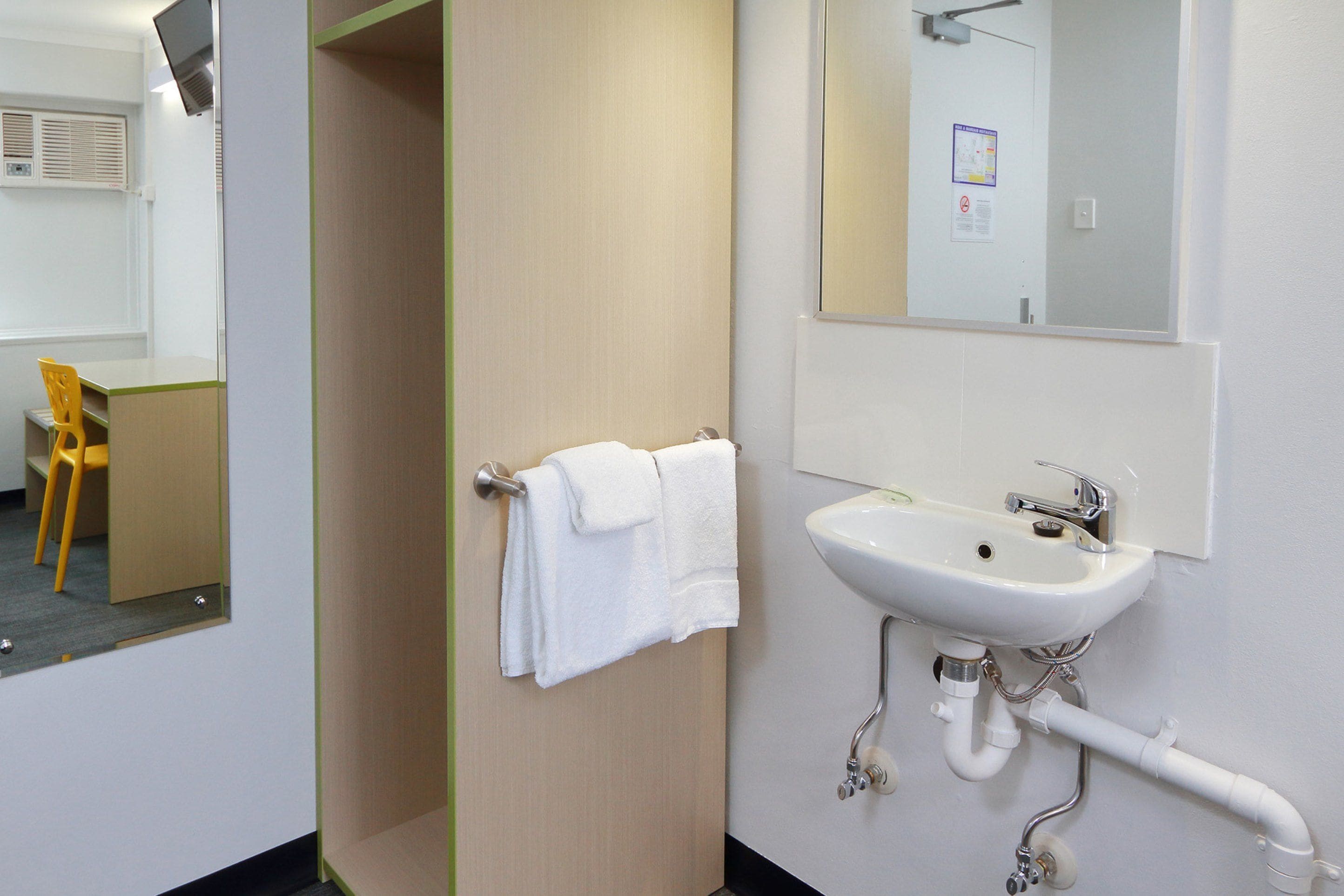 Uma casa de banho de hotel com lavatório, espelho e porta-toalhas.