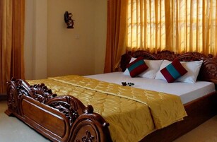 Quarto com cama de madeira, colcha amarela e almofadas coloridas.