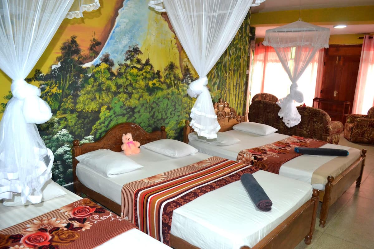 Quarto de hotel com duas camas, cada uma com um corredor de dossel e um edredom estampado com flores.