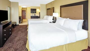 Quarto de hotel com duas camas, uma televisão, uma escrivaninha e um banheiro visível ao fundo.