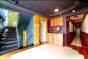 Um corredor amplo com escada, área de cozinha com armários de madeira e vista para o verde lá fora.