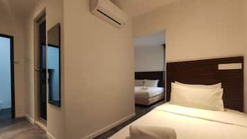 Quarto de hotel com uma cama grande, cabeceira de madeira, ar condicionado fixado na parede e um espelho.