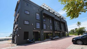 Um edifício moderno de vários andares com telhado plano, grandes janelas e área de entrada pavimentada.