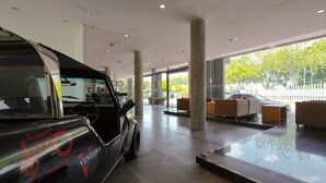 Um lobby moderno com um veículo preto, pilares imponentes e áreas de estar.