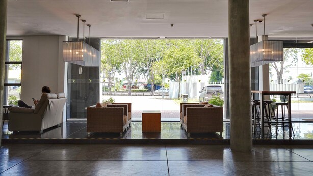 Um lobby moderno com parede de vidro, área de estar e vista para a rua.