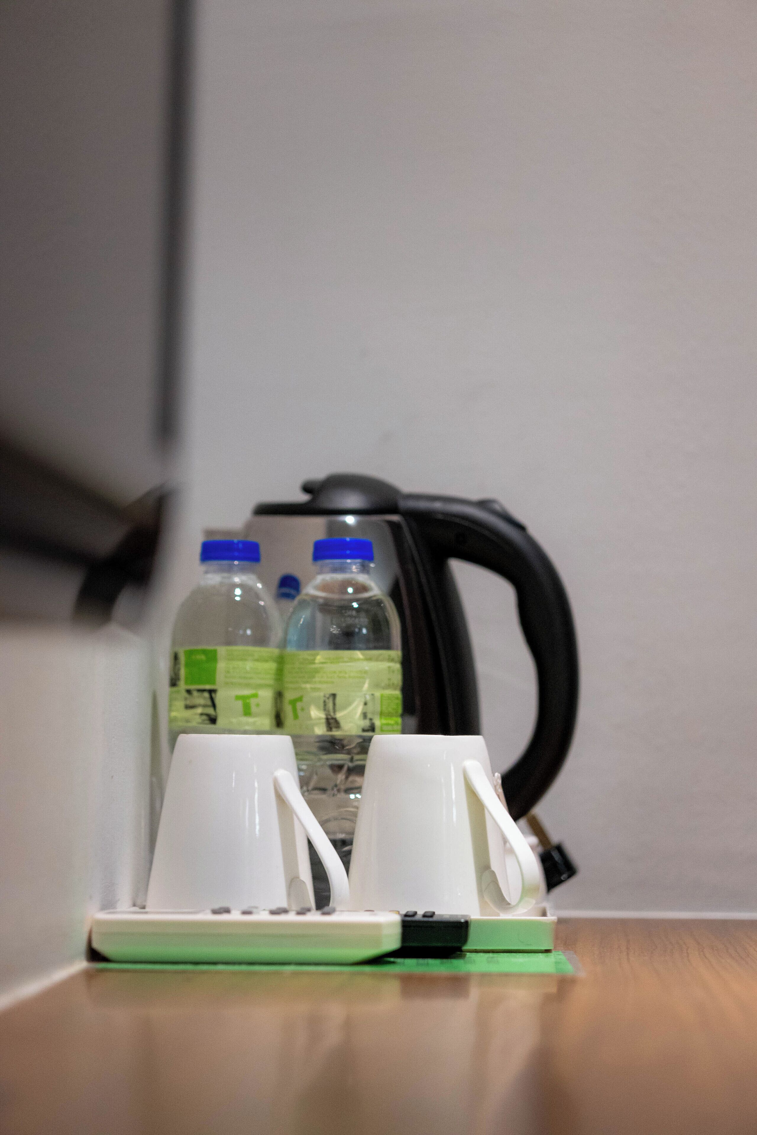 Uma cafeteira, duas garrafas de água e duas chávenas brancas sobre uma mesa.