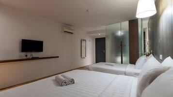 Quarto de hotel com duas camas, uma TV de tela plana na parede, um espelho e um lustre.