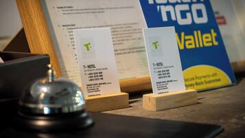Dois cartões informativos do T+ Hotel em suportes de madeira, com um letreiro de 'Touch 'N Go Wallet' ao fundo.