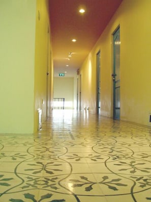 Um corredor comprido e estreito com ladrilhos estampados no chão e paredes amarelas.