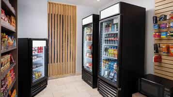 Quarto limpo e moderno com frigorífico, micro-ondas e máquina de vendas, e uma parede de ripas de madeira.