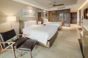 Quarto de hotel com uma cama grande, uma escrivaninha, uma cadeira e um abajur.
