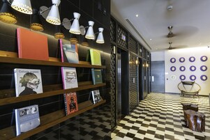 Um interior moderno com piso xadrez, uma estante com livros e uma parede decorativa com padrões circulares.