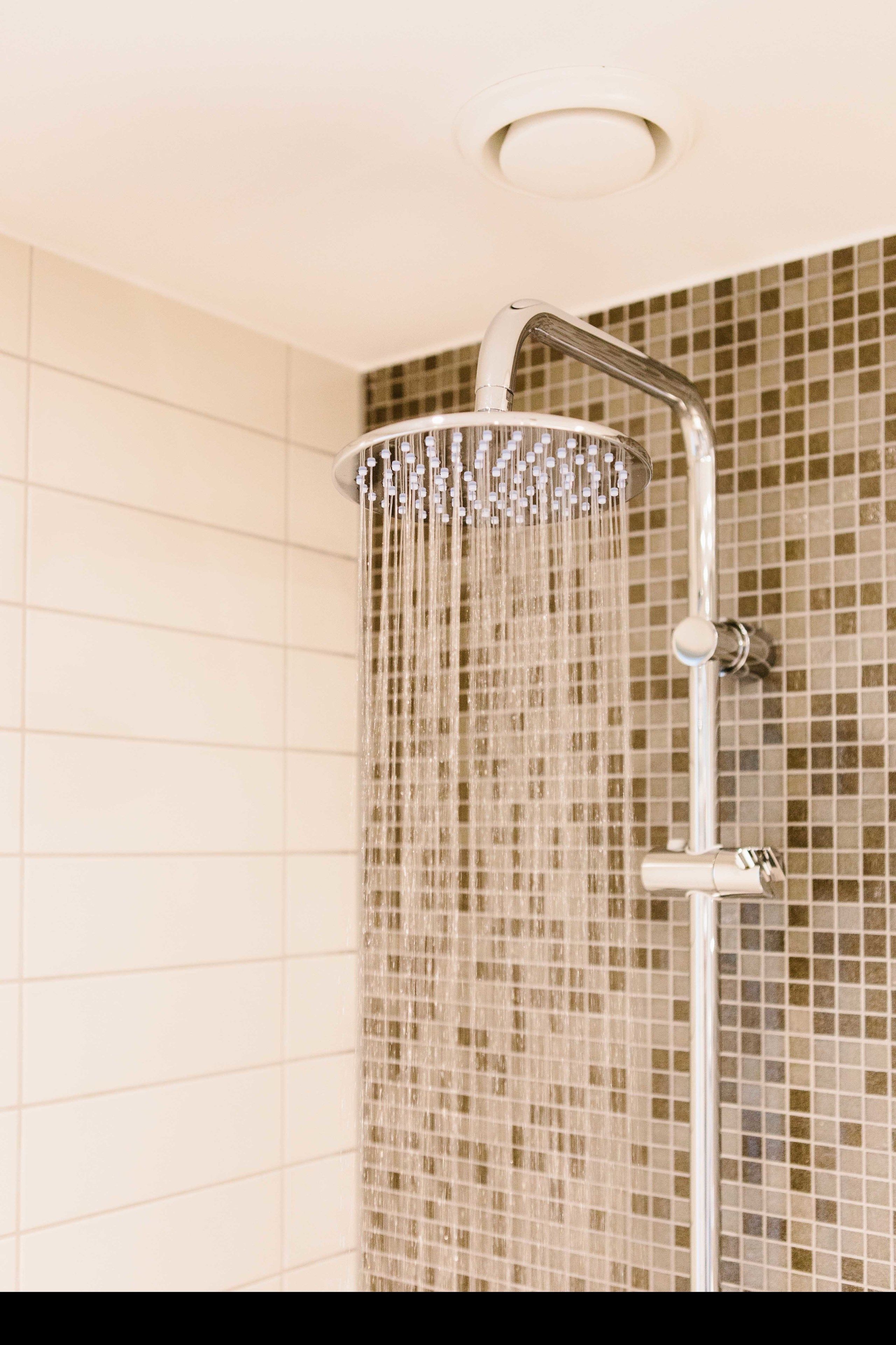 Um chuveiro com design moderno, apresentando um chuveiro curvo e parede revestida com mosaico.