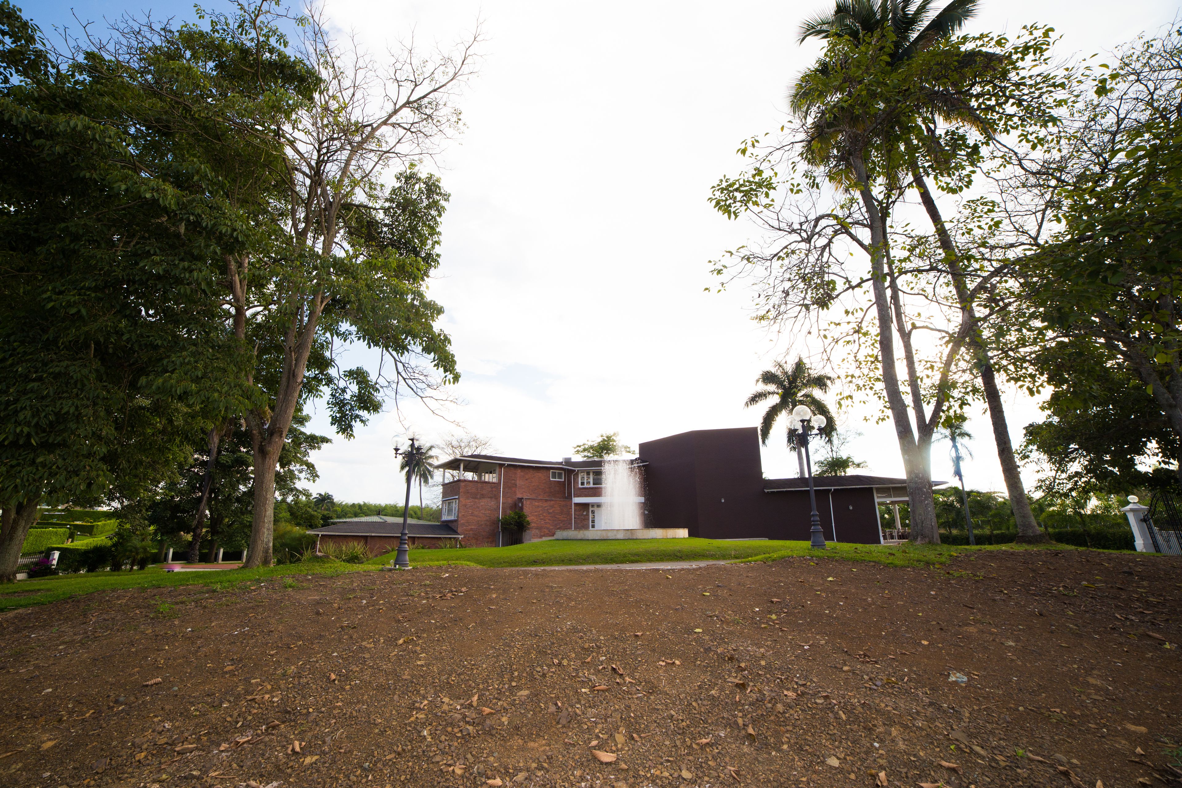 Um edifício com fachada de tijolos, rodeado por árvores e uma área gramada.