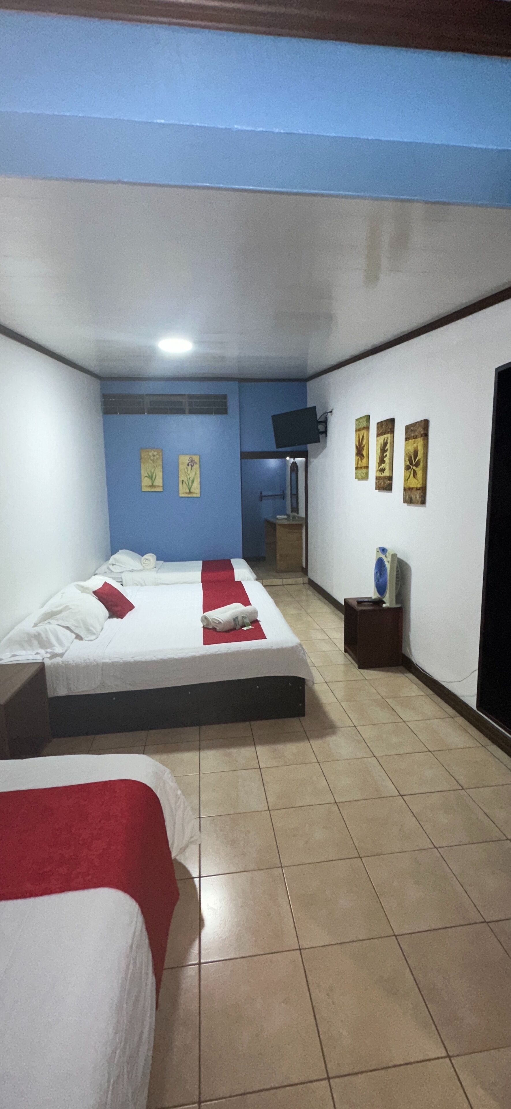 Quarto de hotel com duas camas, televisão de tela plana e obras de arte nas paredes.