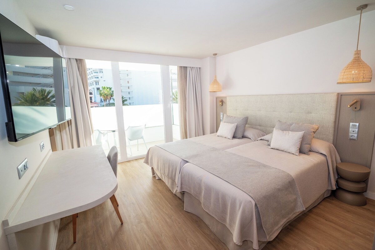 Quarto de hotel com cama, escrivaninha e vista exterior.
