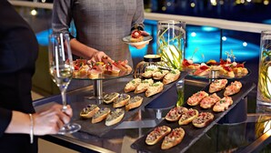 Mesa de buffet com diversos petiscos e alguém servindo comida.