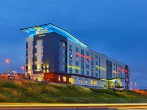 Um hotel moderno com telhado plano, vários andares e uma placa chamativa.