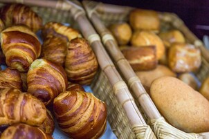 Diversos produtos de panificação, como croissants e baguetes, expostos numa cesta.