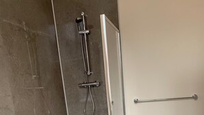 Uma casa de banho moderna com chuveiro, sanita e zona de duche com parede de vidro.