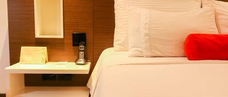 Quarto de hotel com cama, mesa de cabeceira, telefone e espelho.