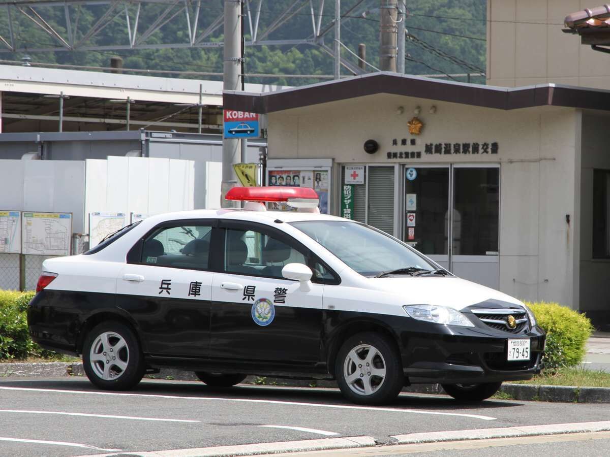 Um carro de polícia estacionado em frente a um edifício com uma placa que diz 'KOBAN'.