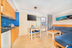 Quarto moderno com cozinha, sala de jantar e sofá.