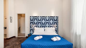 Quarto de hotel com uma cama grande, cabeceira estampada e vista para um corredor.