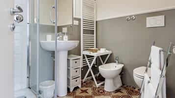 Um banheiro moderno com box de vidro, pia de pedestal, vaso sanitário e porta-toalhas.