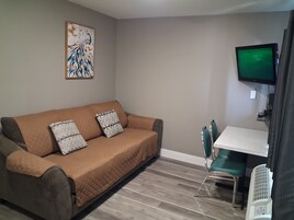 Quarto solteiro júnior, 1 cama Queen | Área de estar | TV de tela plana 32 polegadas com canais digitais, TV, filmes recentes