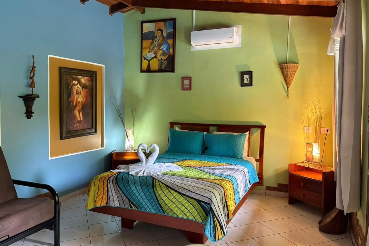 Quarto com cama, cadeira, mesa de cabeceira e ar-condicionado fixado na parede.
