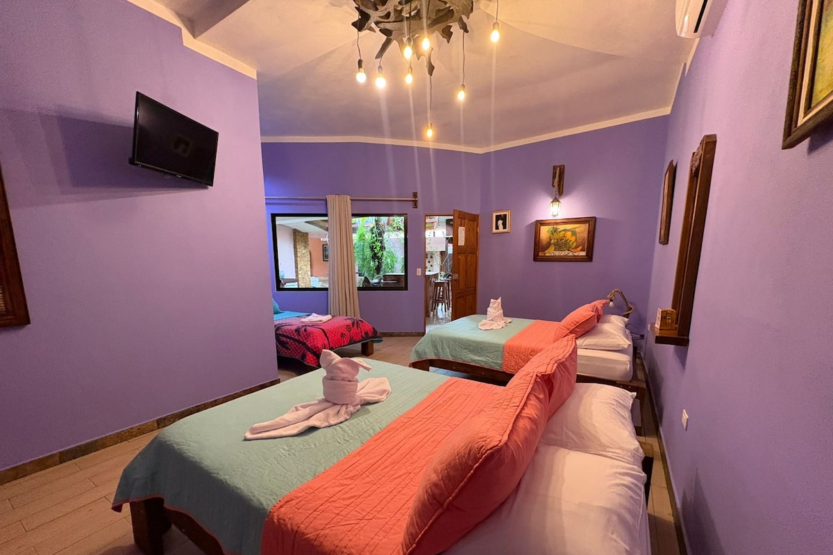 Quarto de hotel com duas camas, televisão e vista para o exterior.