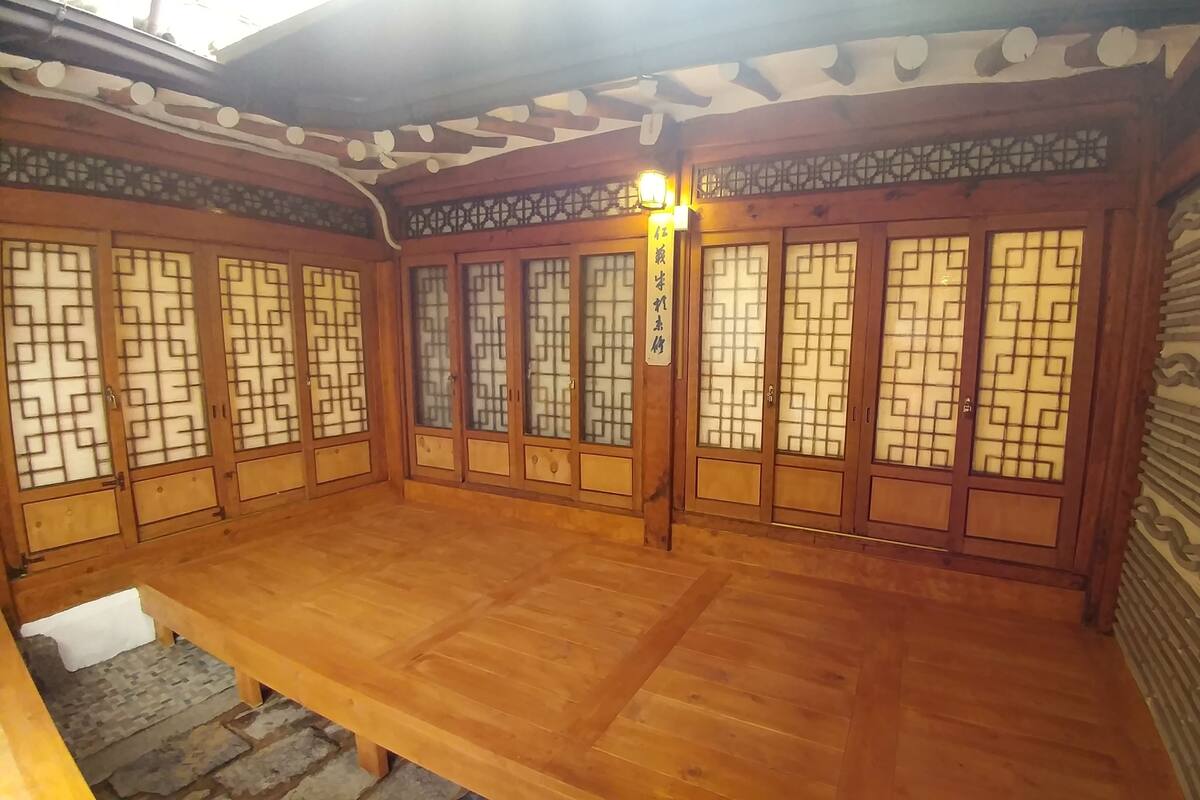 Um quarto japonês tradicional com tatames, portas deslizantes com padrões geométricos e um candeeiro suspenso.
