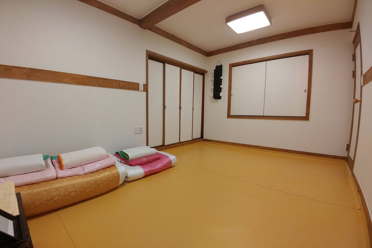 Quarto com tatames, futon, portas de correr e luminária no teto.