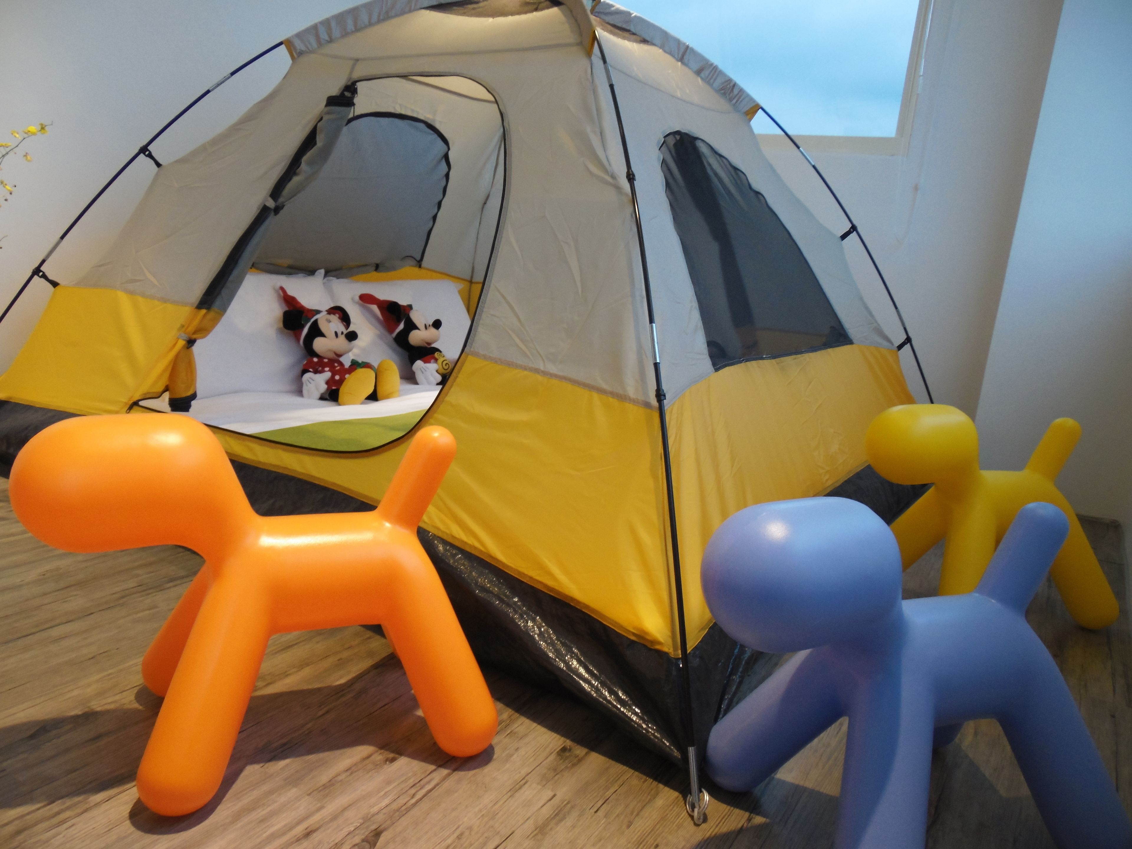 Uma tenda com área de dormir, brinquedos macios e uma pequena mesa.